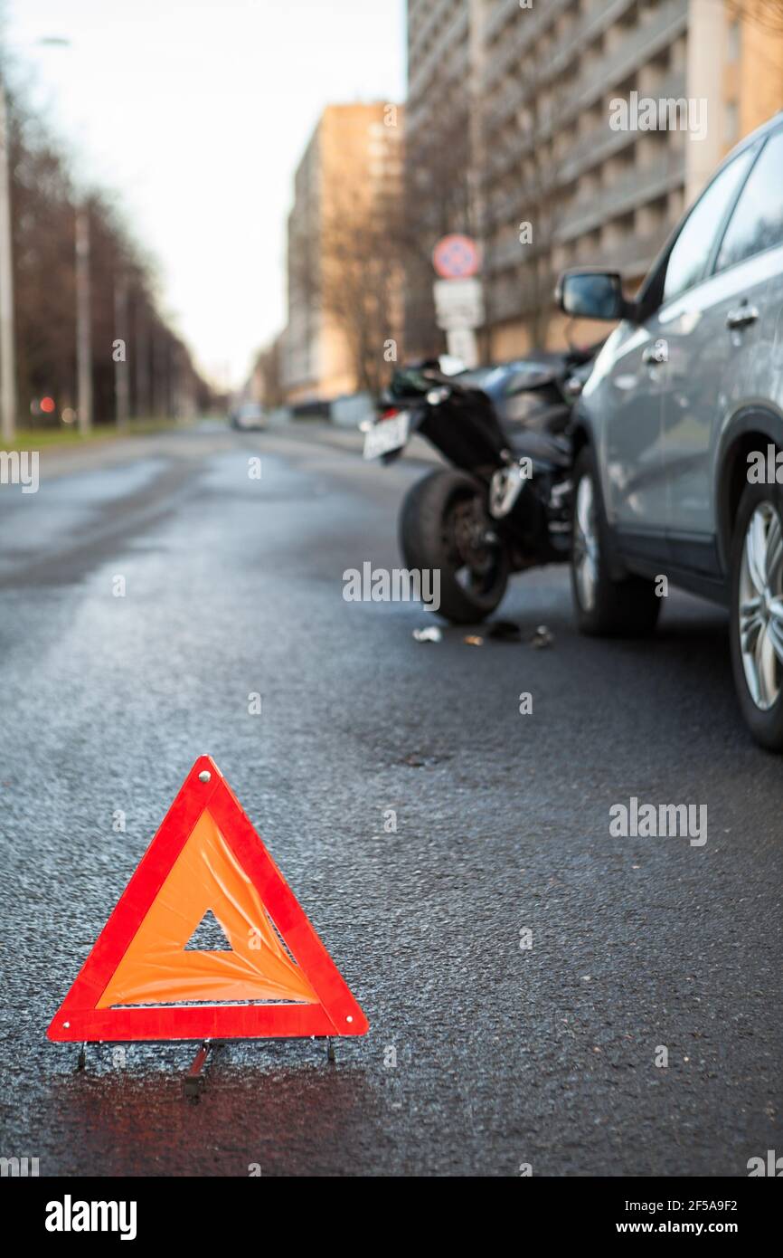 Triangular safety reflector is on asphalt road, sign is on the distance ...