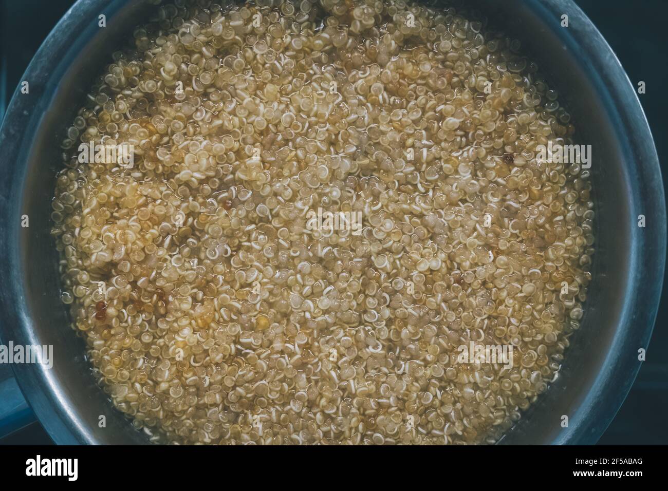 Pot cooking quinoa grains viewed from above, faded colors and film ...