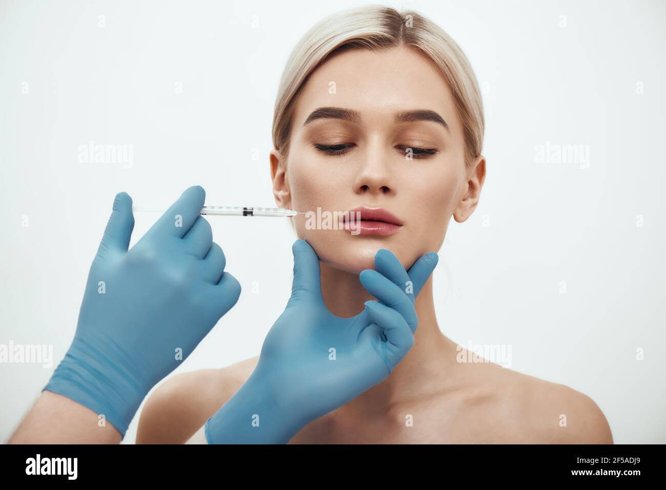 Botox injection. Young attractive woman keeping her eyes closed while ...