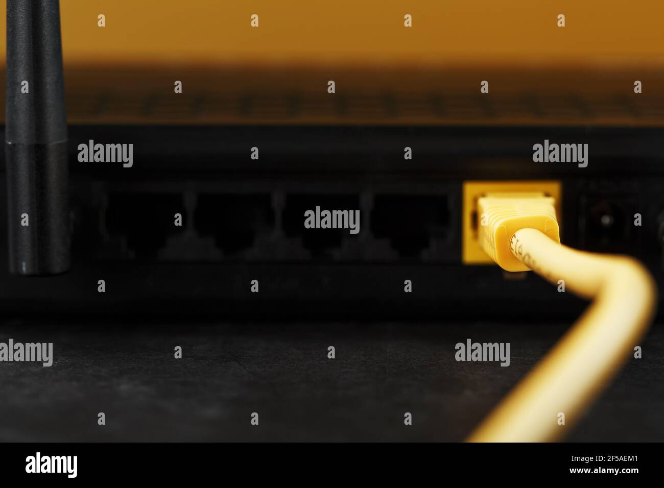 A yellow patch cord is inserted into the Wi-Fi port of the router to ...