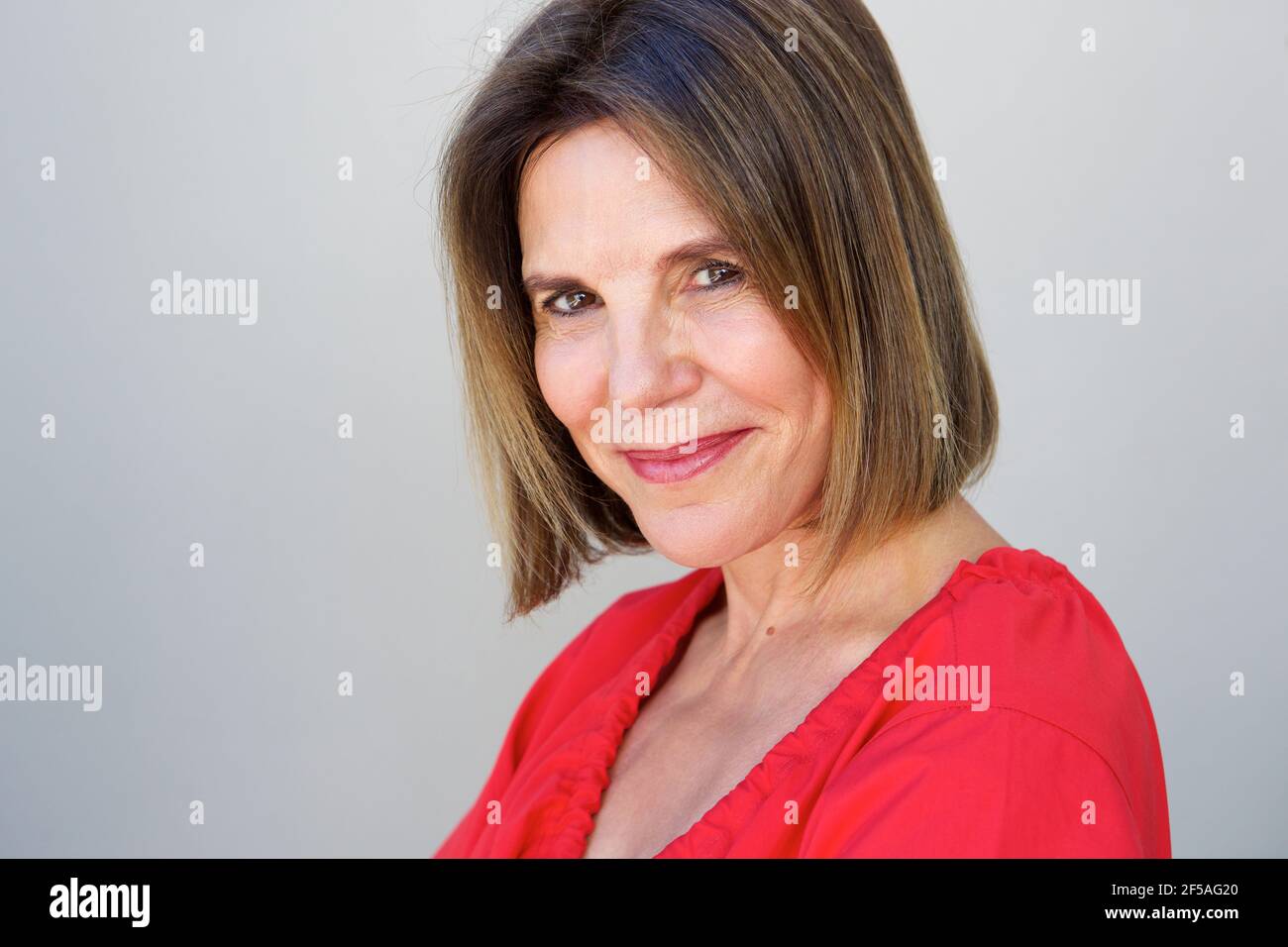 Portrait of attractive older woman smiling against gray background Stock Photo - Alamy