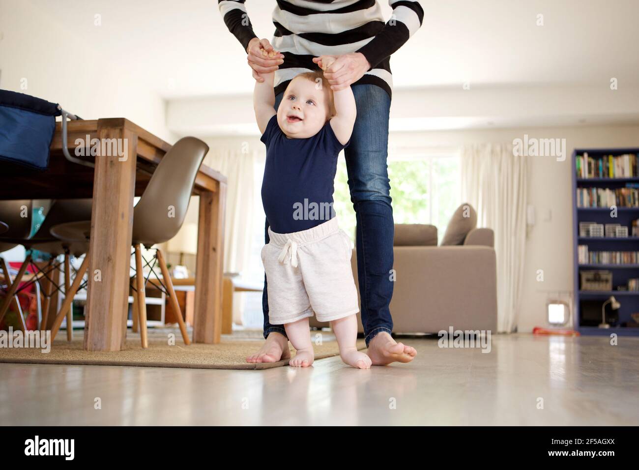 Portrait of happy little baby boy learning to walk with mother help at ...