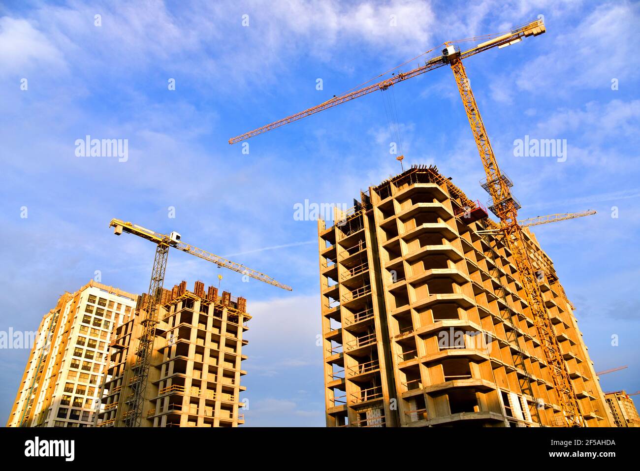 Tower cranes working at construction site on blue sky background ...