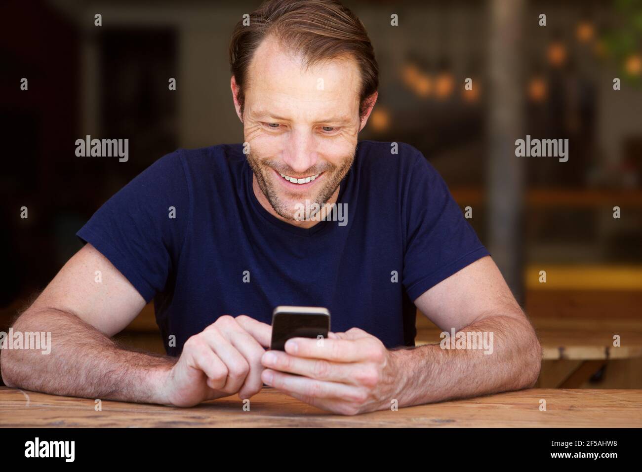 Portrait of handsome man holding mobile phone and sending text message ...