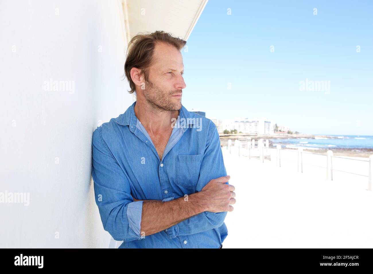 Portrait of male fashion model leaning against wall outdoors Stock ...