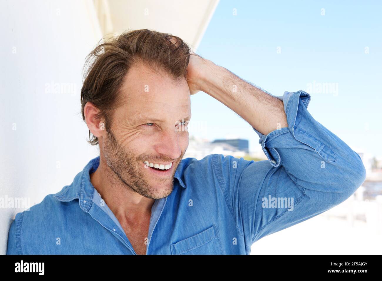 Close up portrait of attractive male model smiling with hand in hair ...