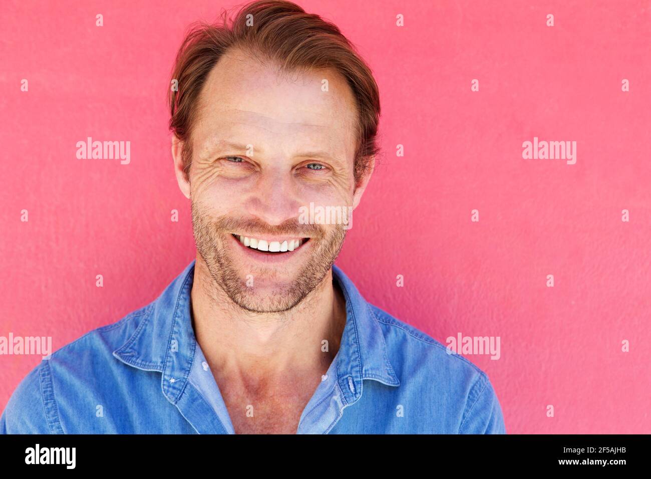 Portrait of handsome male model smiling against pink background Stock ...