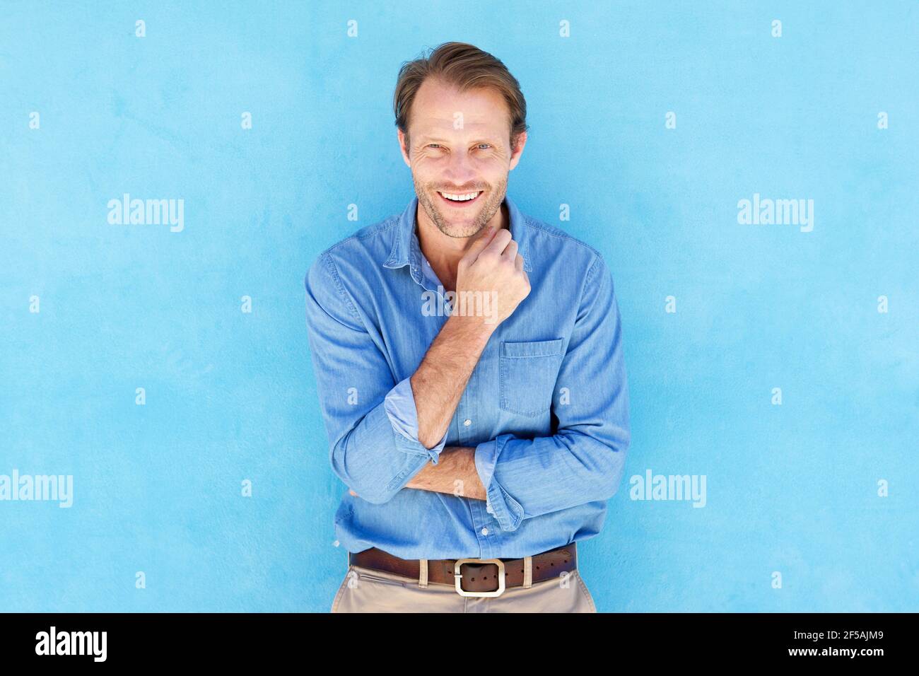 Portrait of happy man laughing against blue background Stock Photo - Alamy