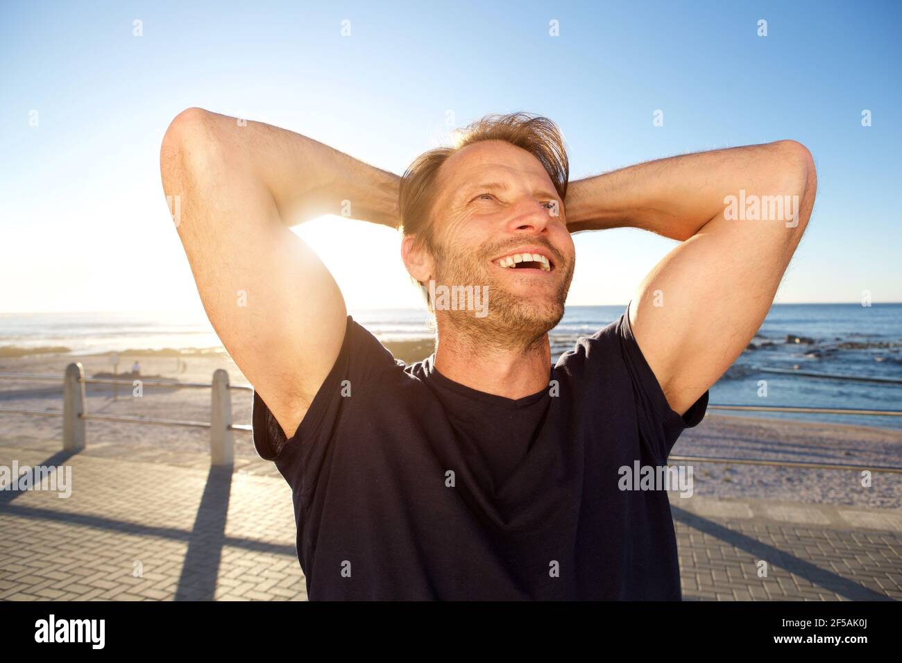 Portrait of handsome fitness man laughing with hands behind head Stock ...