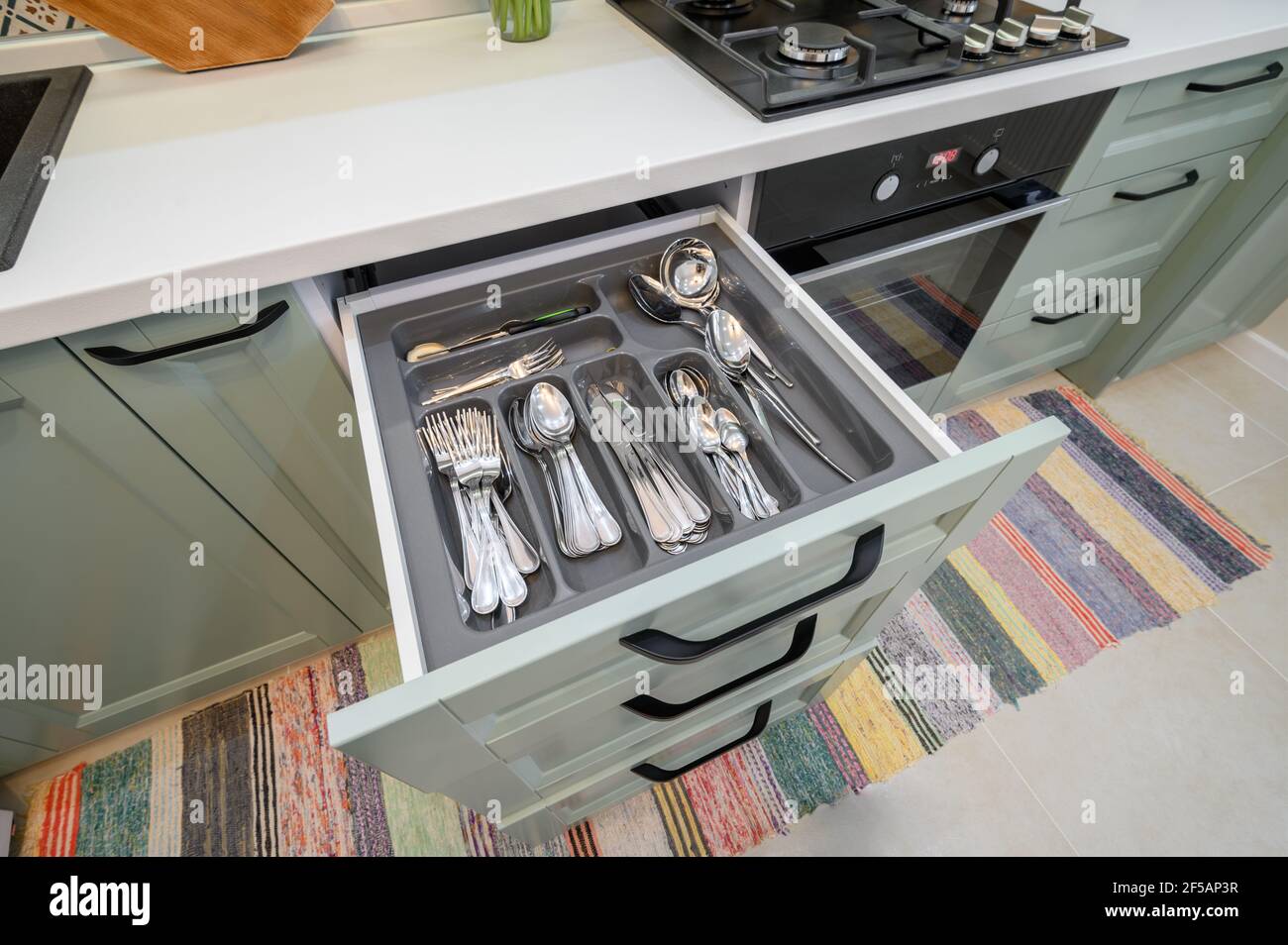 Drawer pulled out in cabinet at luxury teal and white modern kitchen ...