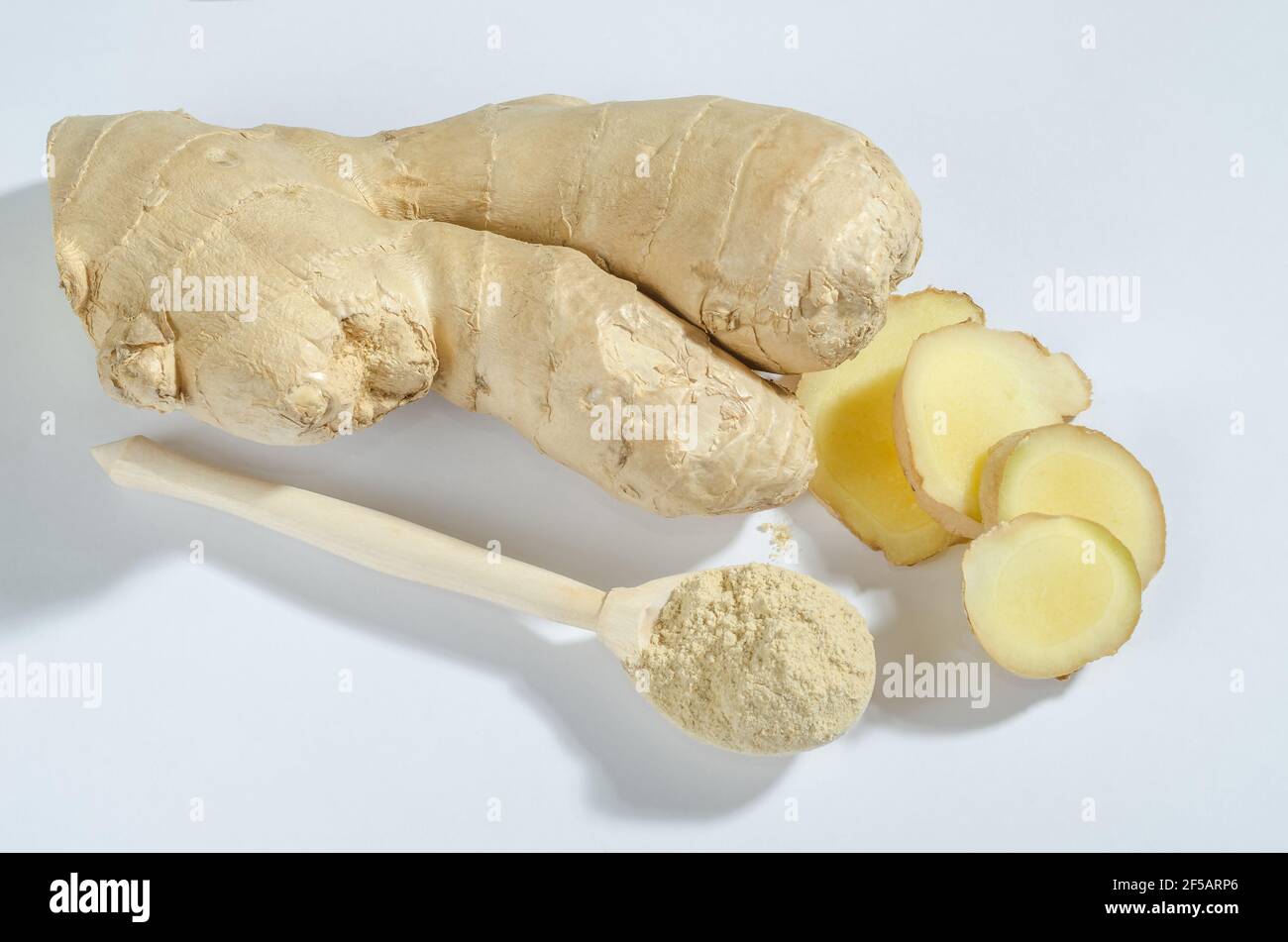 Ginger root with chopped wedges and dry powder on white plate with hard ...