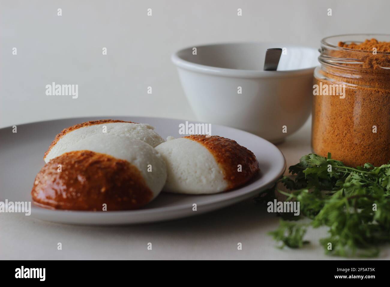 Idli half covered with podi chutney also named gunpowder. Podi is made ...