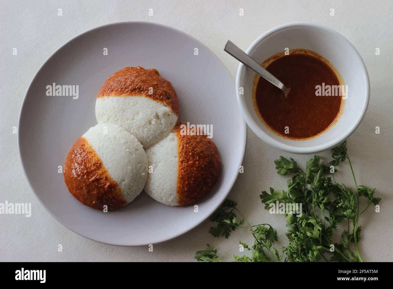 Idli half covered with podi chutney also named gunpowder. Podi is made ...