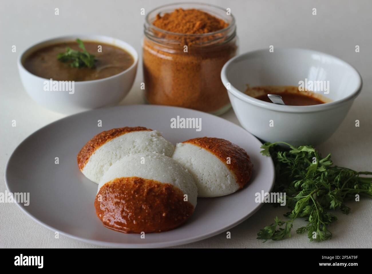 Idli half covered with podi chutney also named gunpowder. Podi is made ...