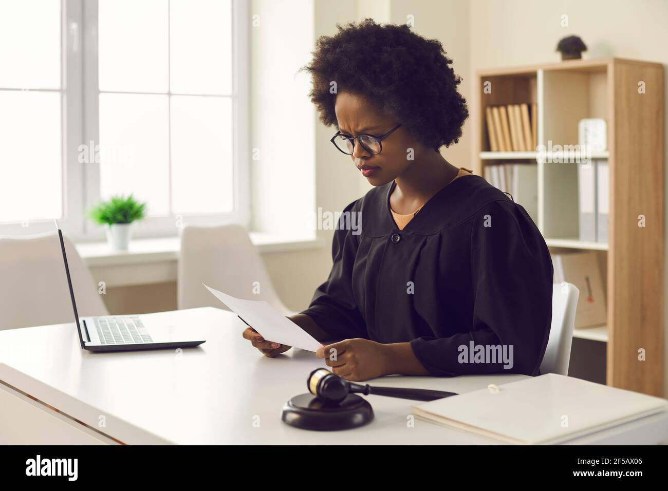 Frowning african american female judge reading legal paper document at ...
