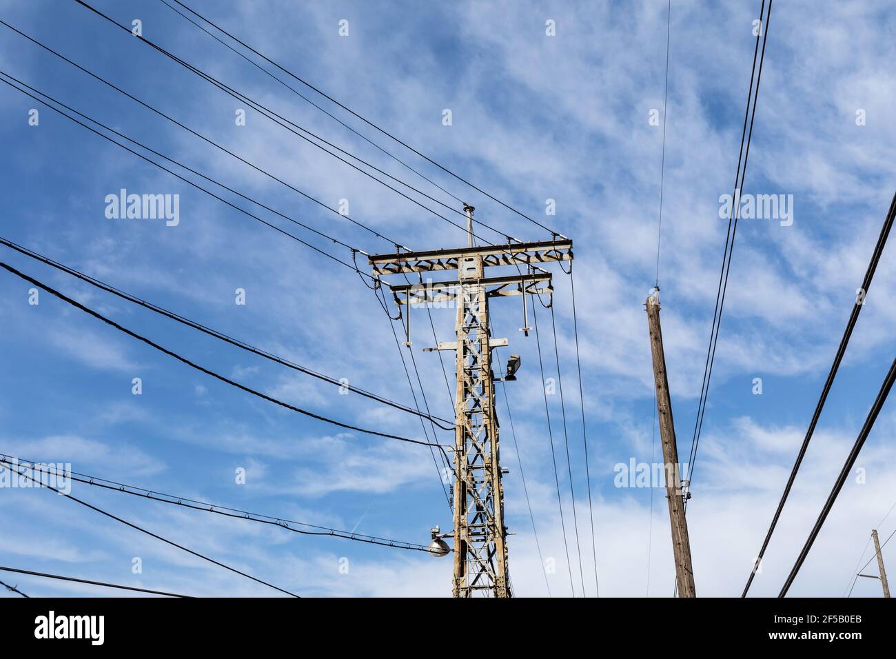 Old rusted industrial metal power line tower alongside a traditional ...