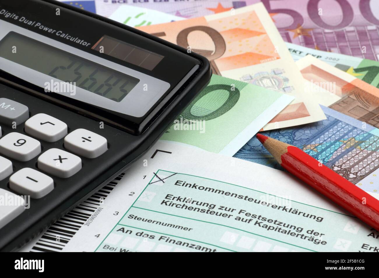 Closeup of a tax form and calculator on a spread of Euro banknotes ...