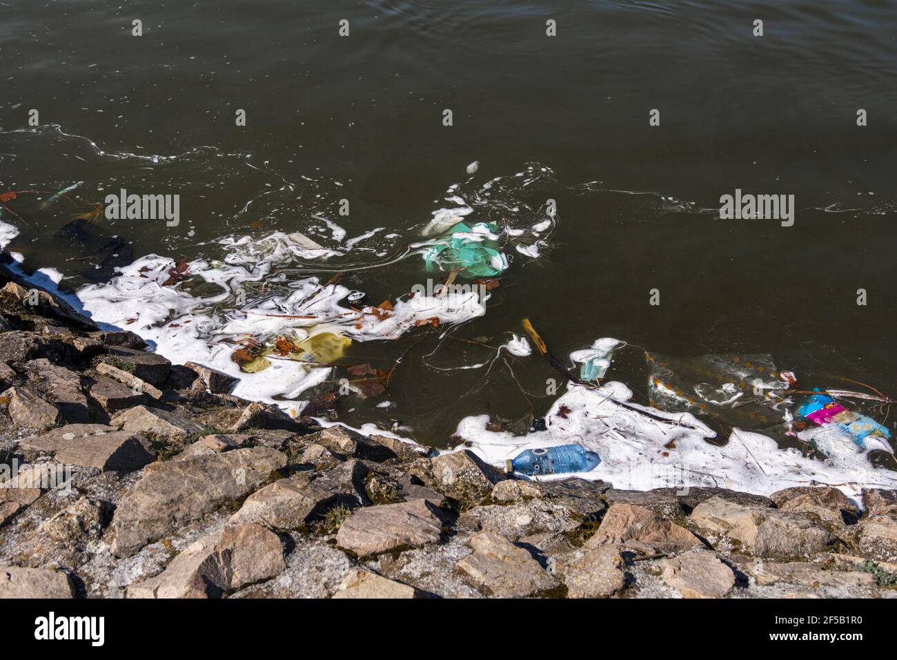Closeup shot of garbage with plastic bags and bottles in the lake - the ...