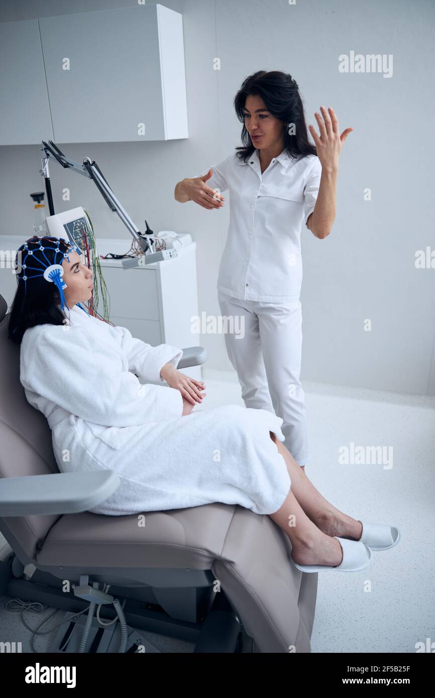 Qualified neurophysiologist and her patient discussing the upcoming EEG ...