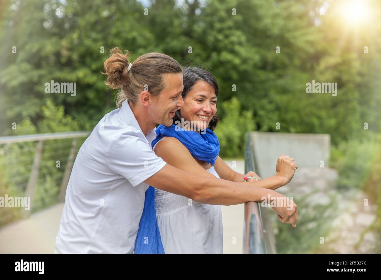 Cute Caucasian couple hanging a lock on the bridge as a sign of eternal ...