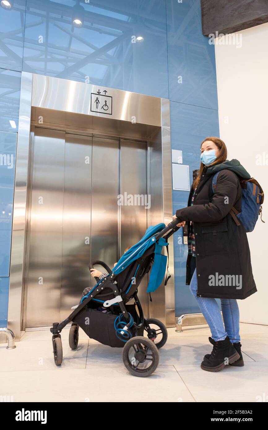 Caucasian mother waiting the elevator with her daughter sitting in ...