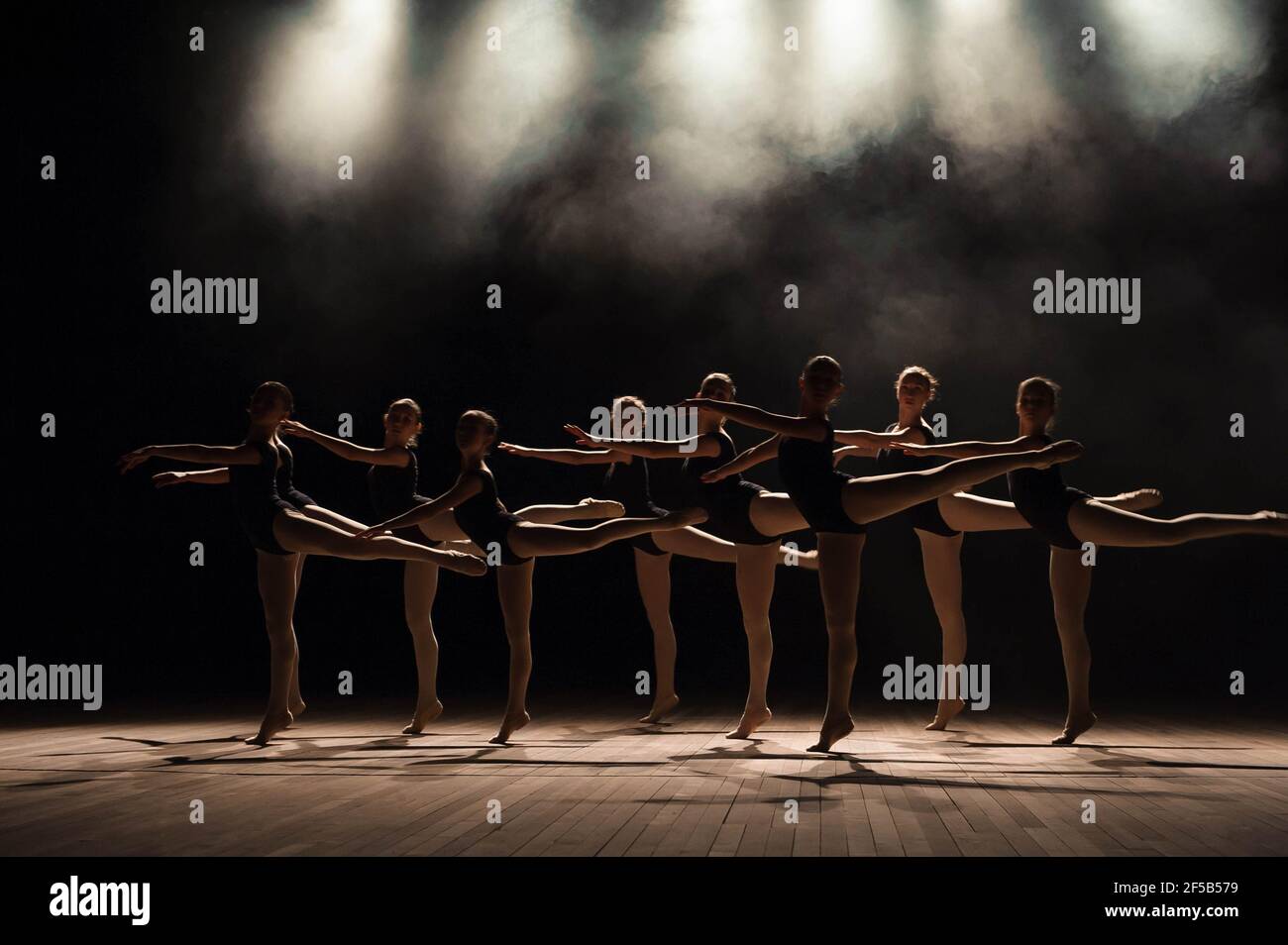 Ballet class on the stage of the theater with light and smoke. Children ...