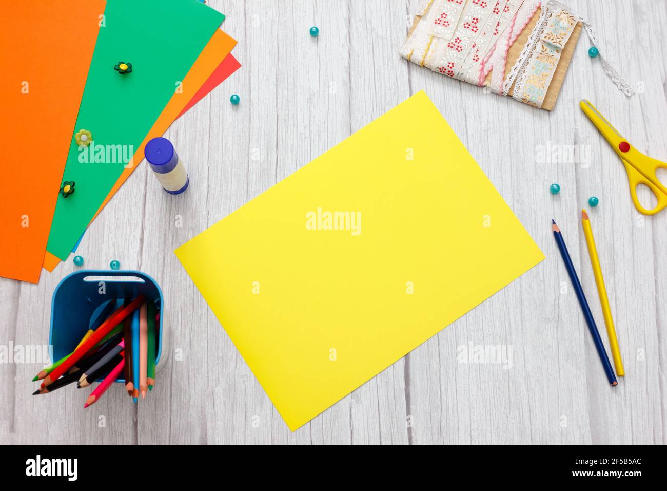 Objects on the table top view. Yellow sheet of paper, pencils. Top view ...