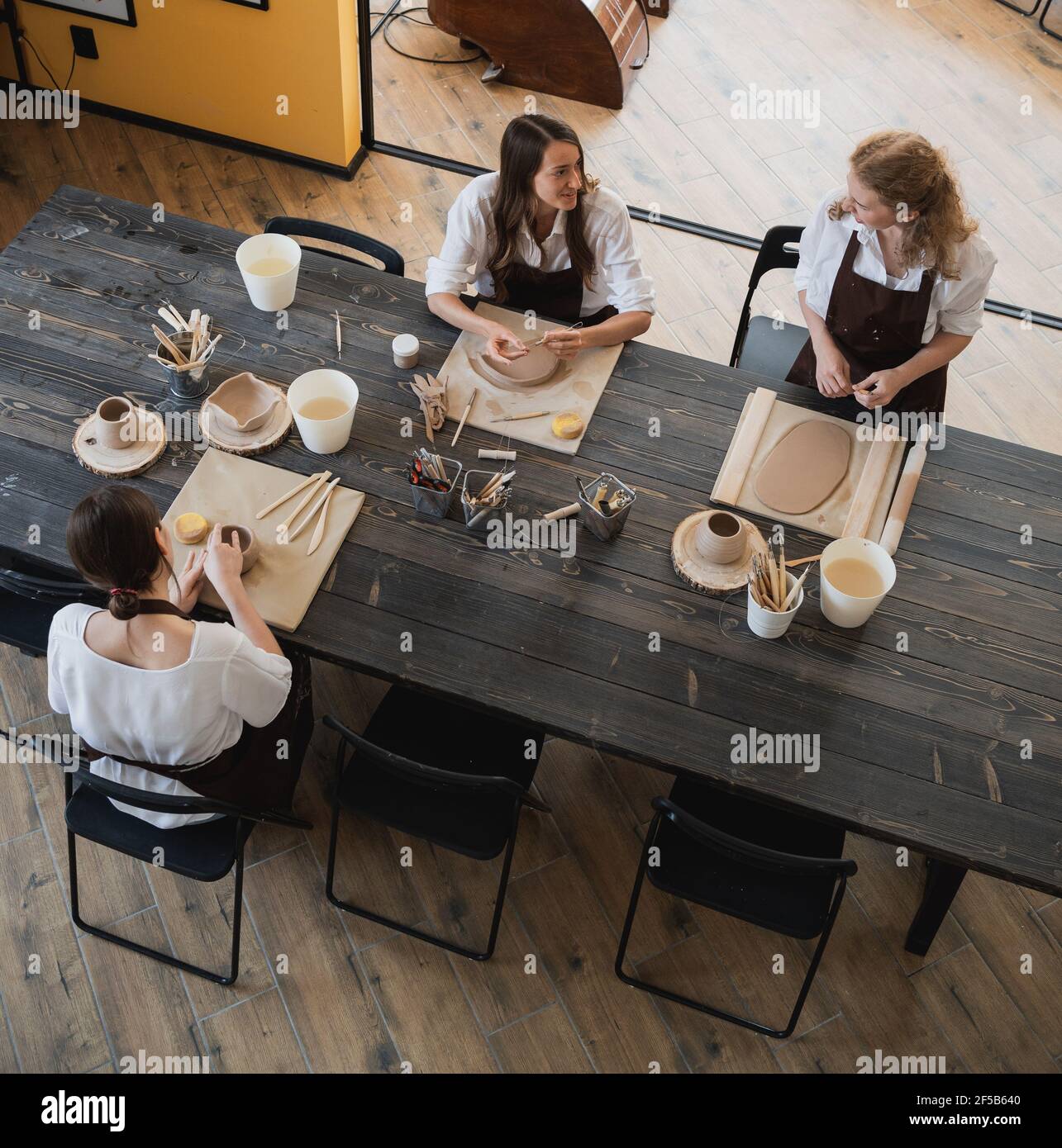 Caucasian female best friends pottery artists decorating a ceramic pod ...