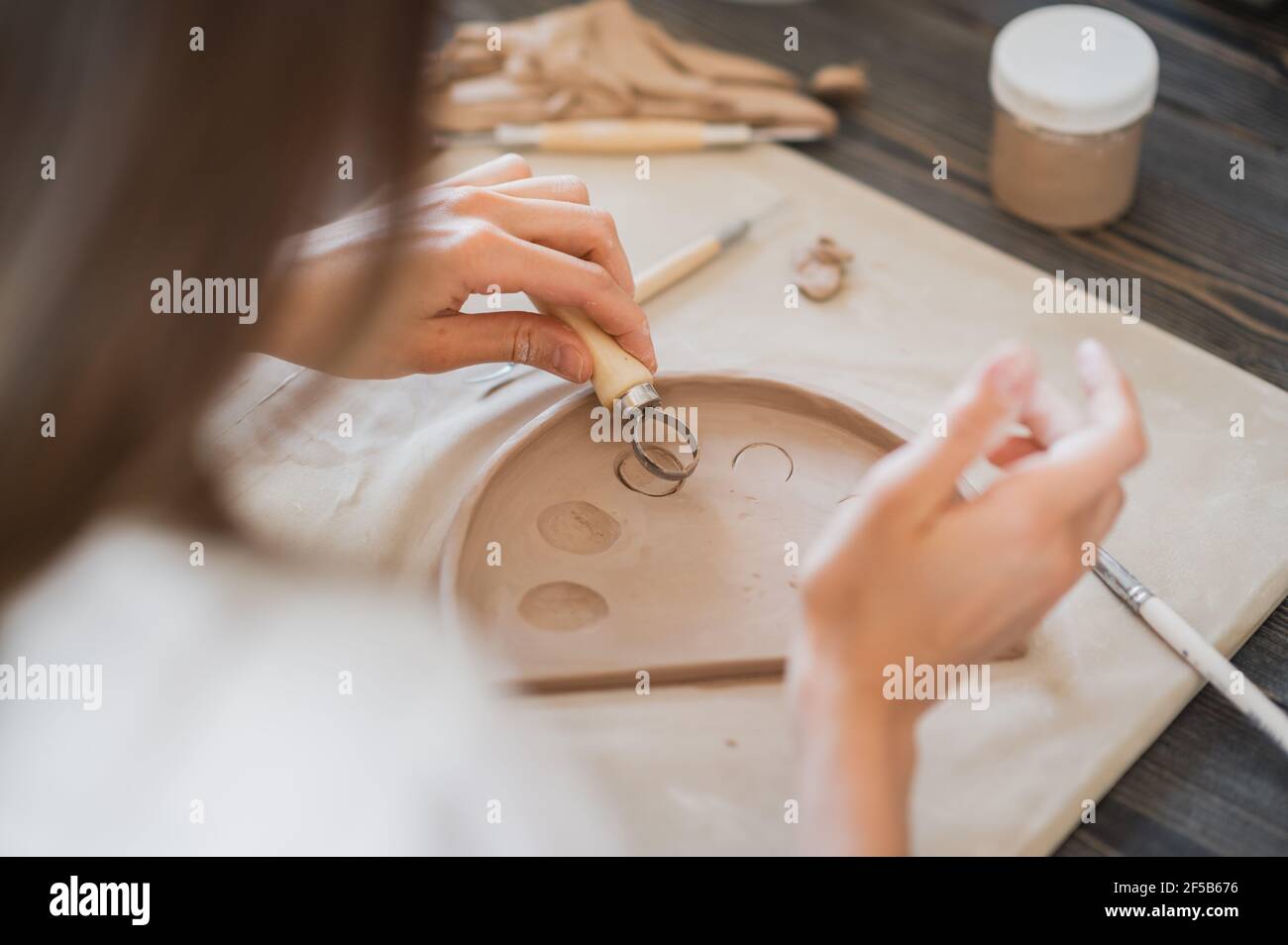 Professional female potter shaping and carving parts pottery workshop ...