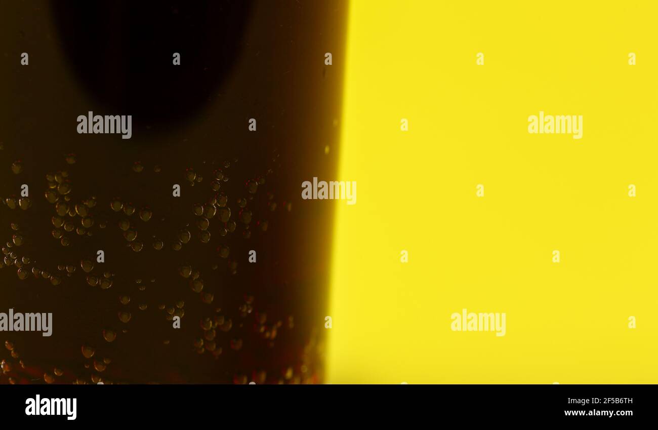 Small bubbles in dark fizzy drink, closeup detail with yellow ...