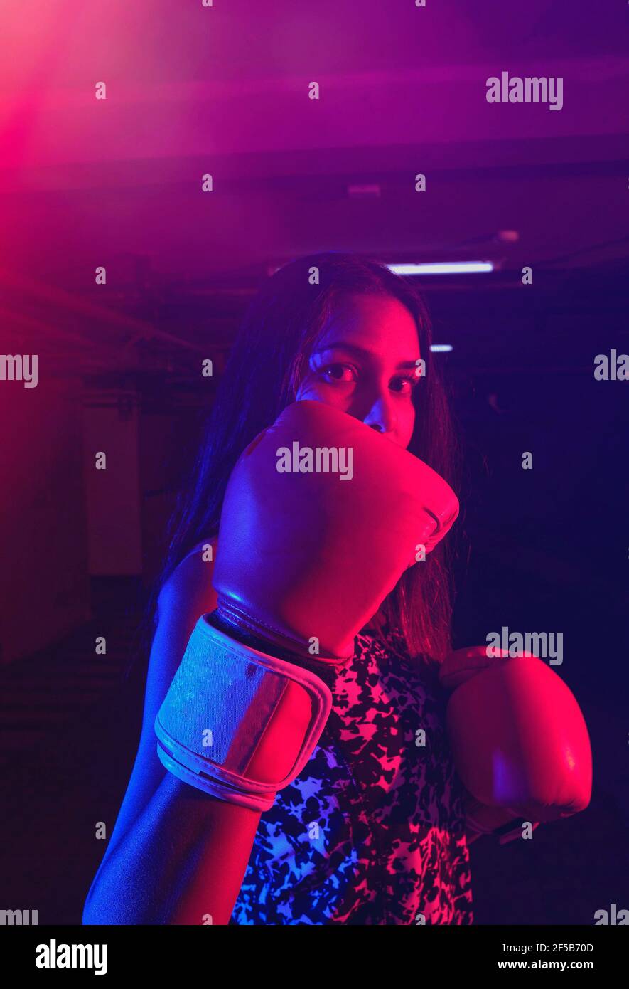 Beautiful female boxer training, red boxing gloves, ring with red and ...
