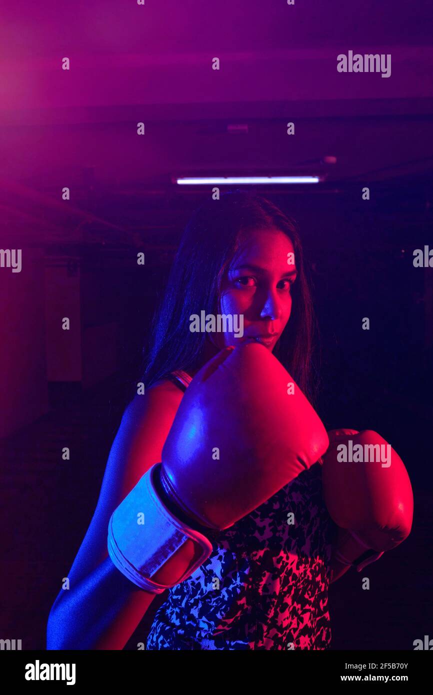 Beautiful female boxer training, red boxing gloves, ring with red and ...