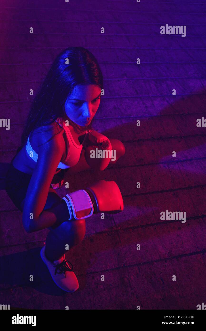 Beautiful female boxer training, red boxing gloves, ring with red and ...