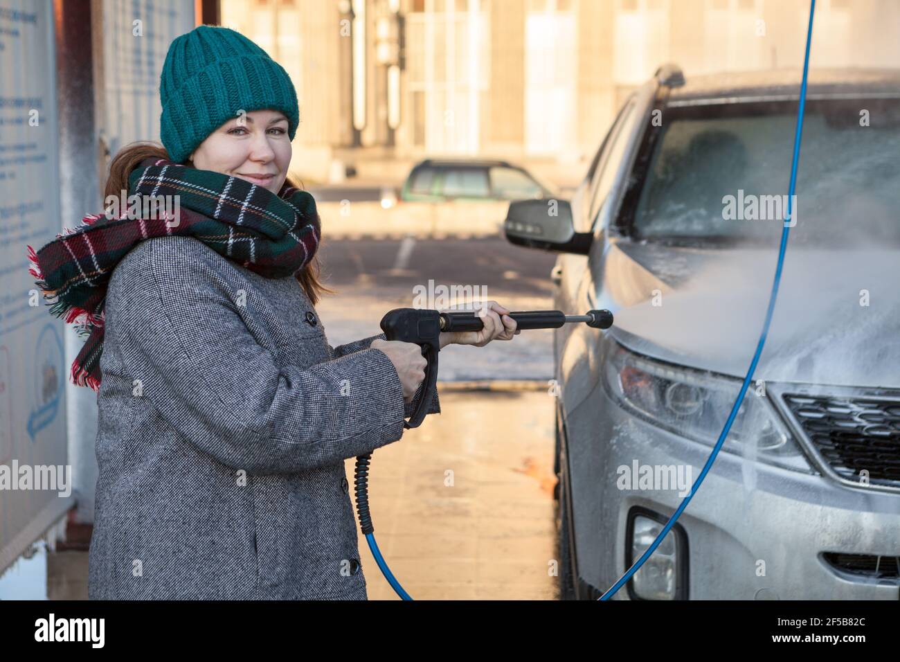 Portrait of adult woman holding high pressure sprayer in hand in a self ...