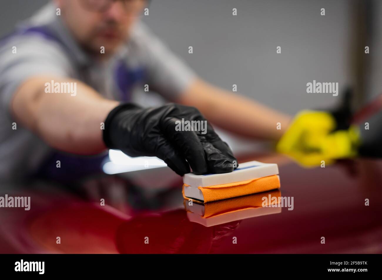 Close-up man applying ceramic coating on the red car at detailing ...