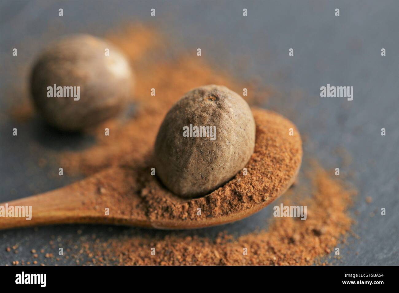 Nutmeg spice.Whole and ground nutmeg in a wooden spoon close-up on a ...