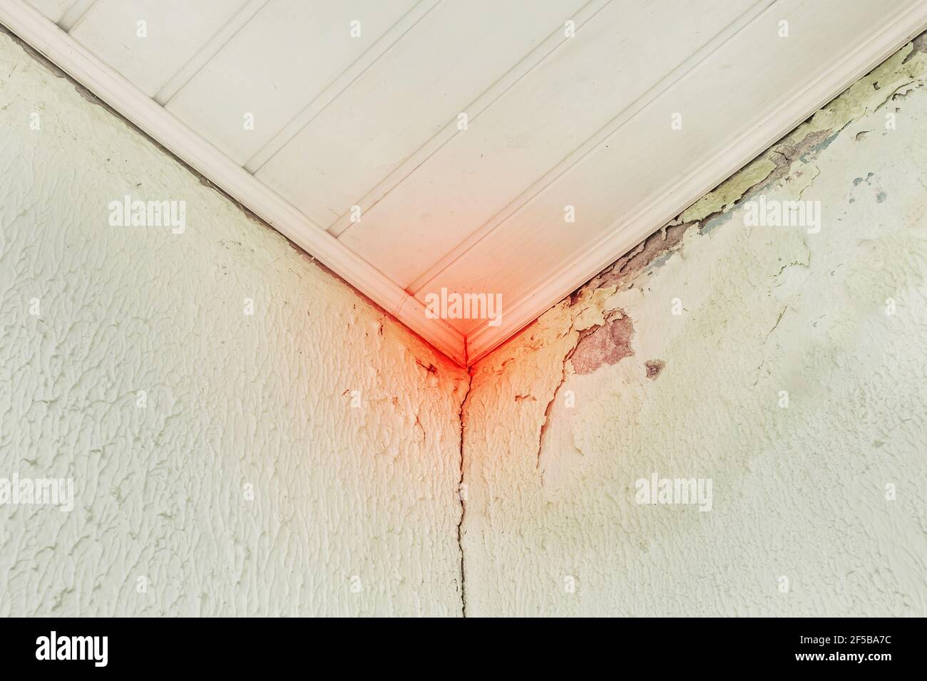 Crack on the old plaster wall surface in the ceiling corner of the ...