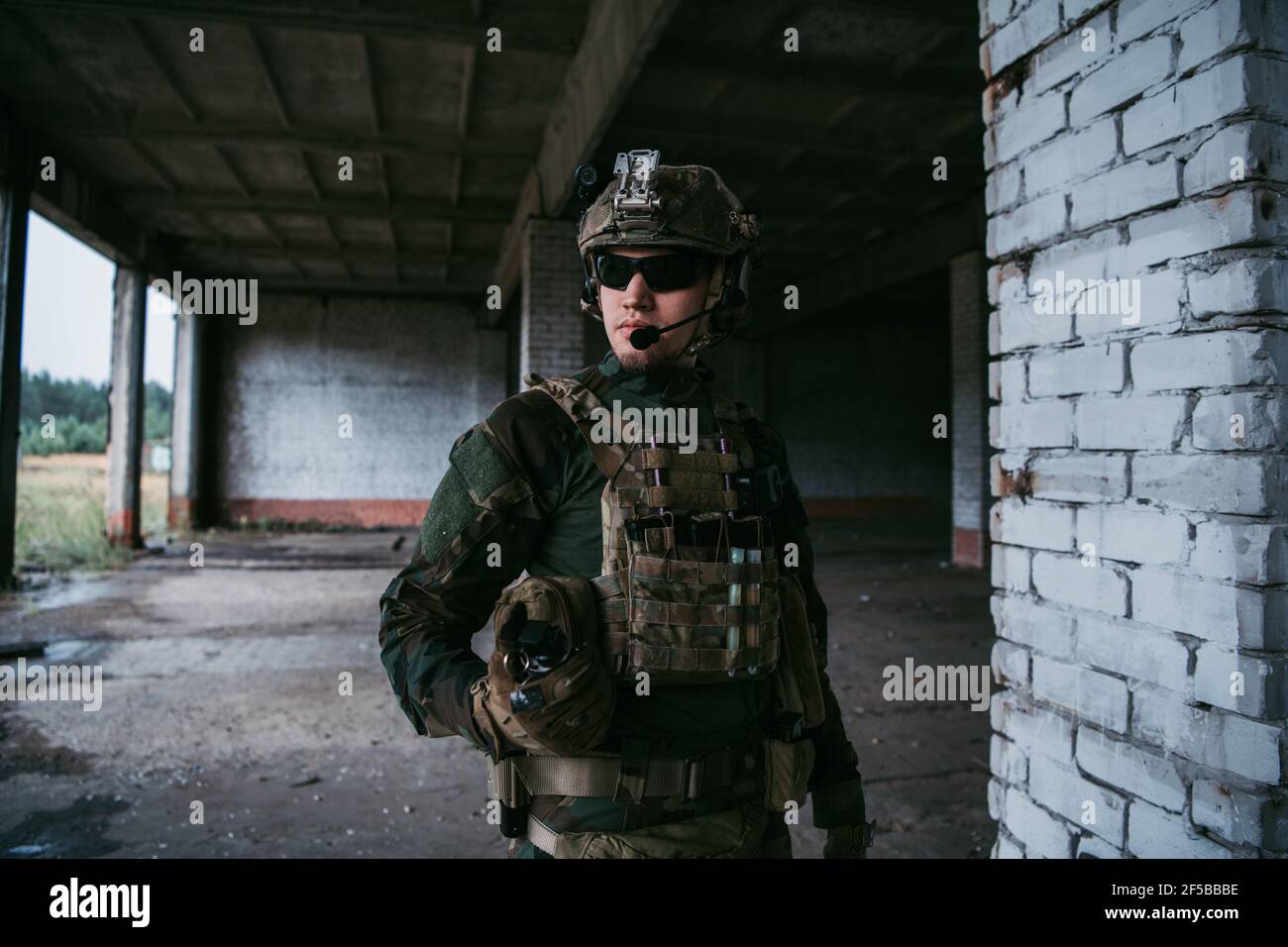 Military man with assault rifle standing inside building, he is ready ...
