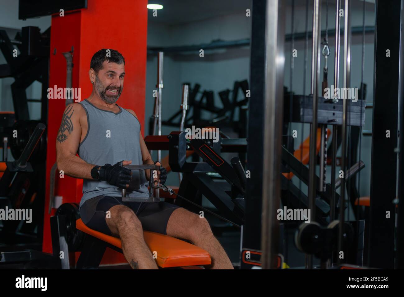 Fitness training in sport gym of active male with beard sitting and ...