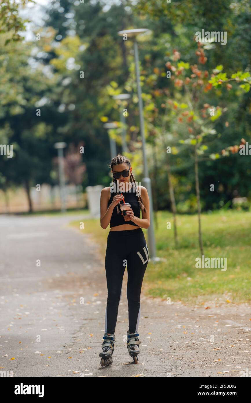 Two women in sportswear rollerblading at the park in sunny weather ...