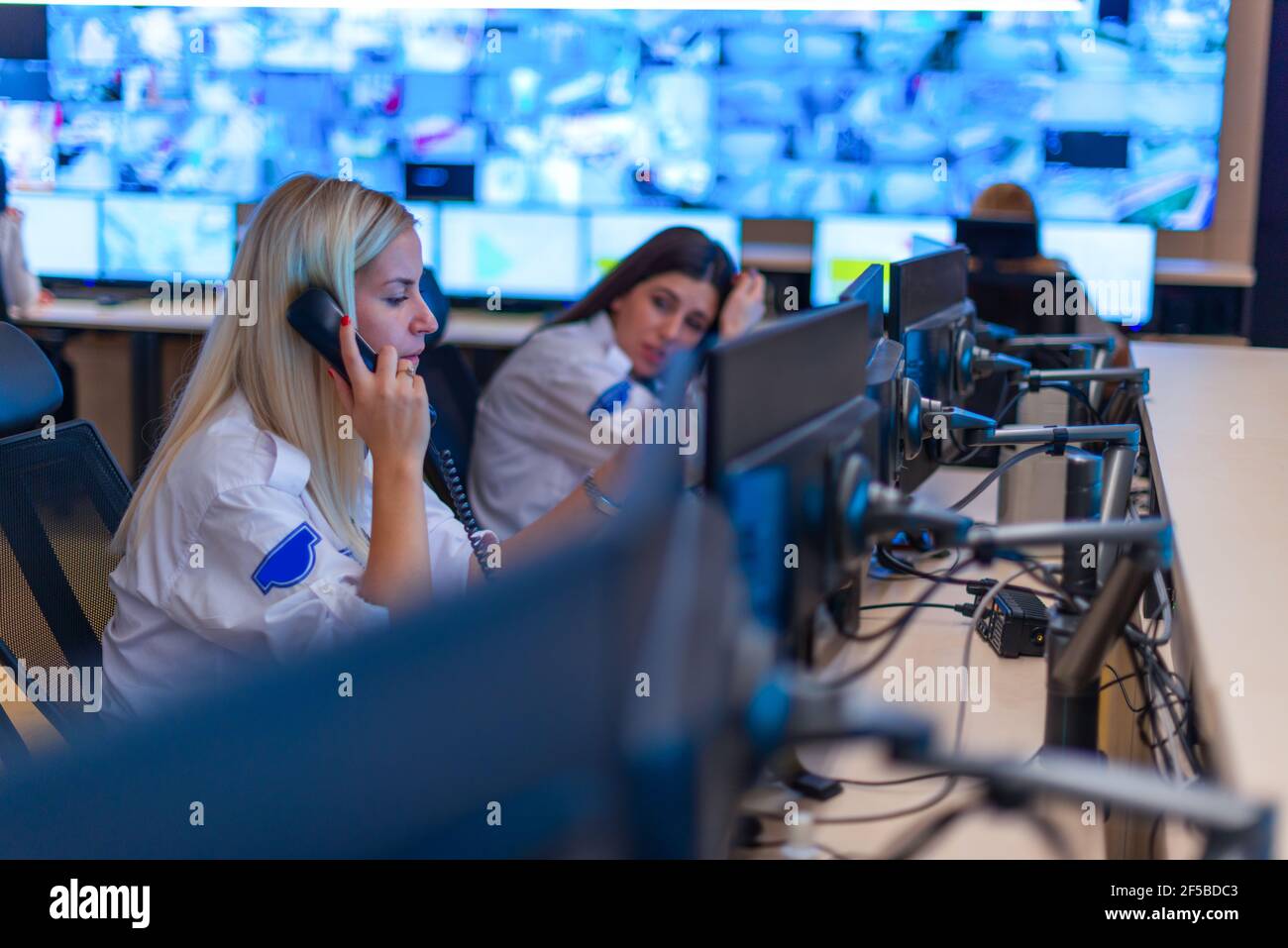 Female security guard operator talking on the phone while watching the ...