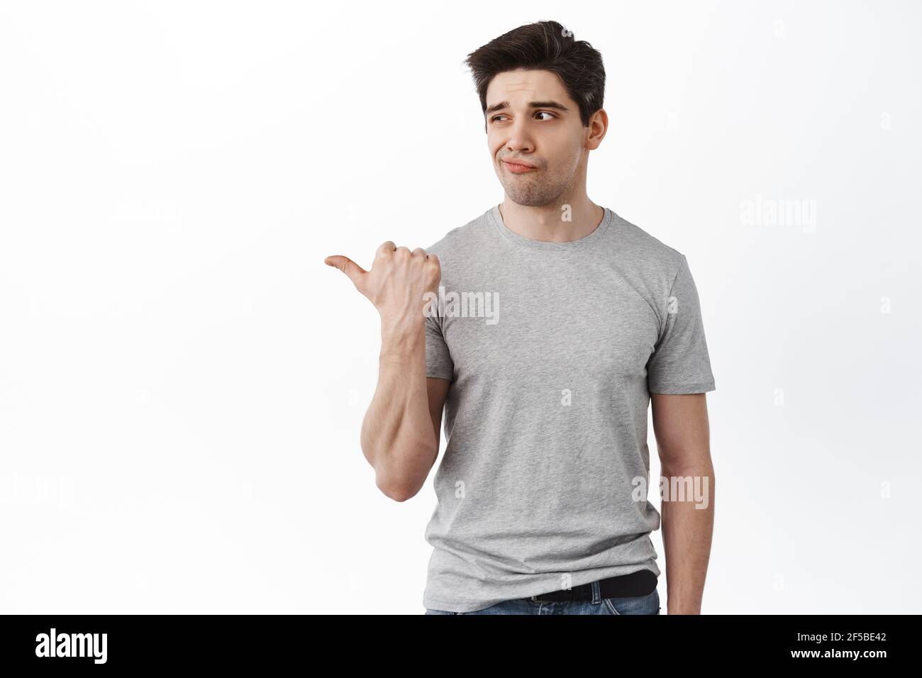 Disappointed and gloomy young man pointing left at bad product, being ...