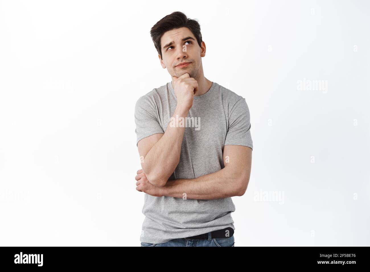 Portrait of handsome man in deep thoughts looking aside, touching chin ...