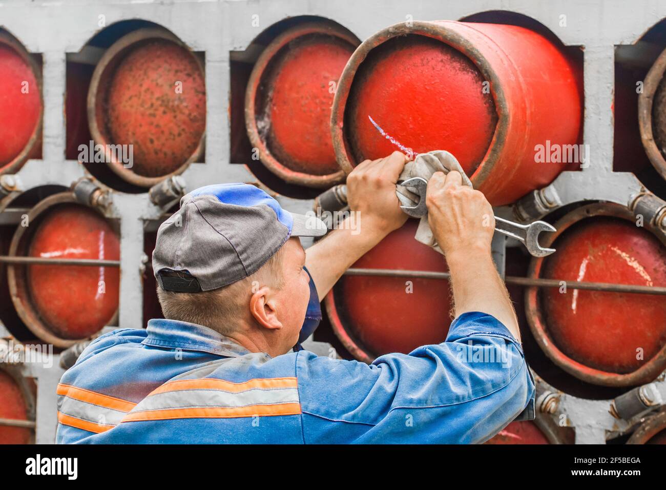 Adult male worker pushing a gas cylinder into a gas machine Stock Photo ...