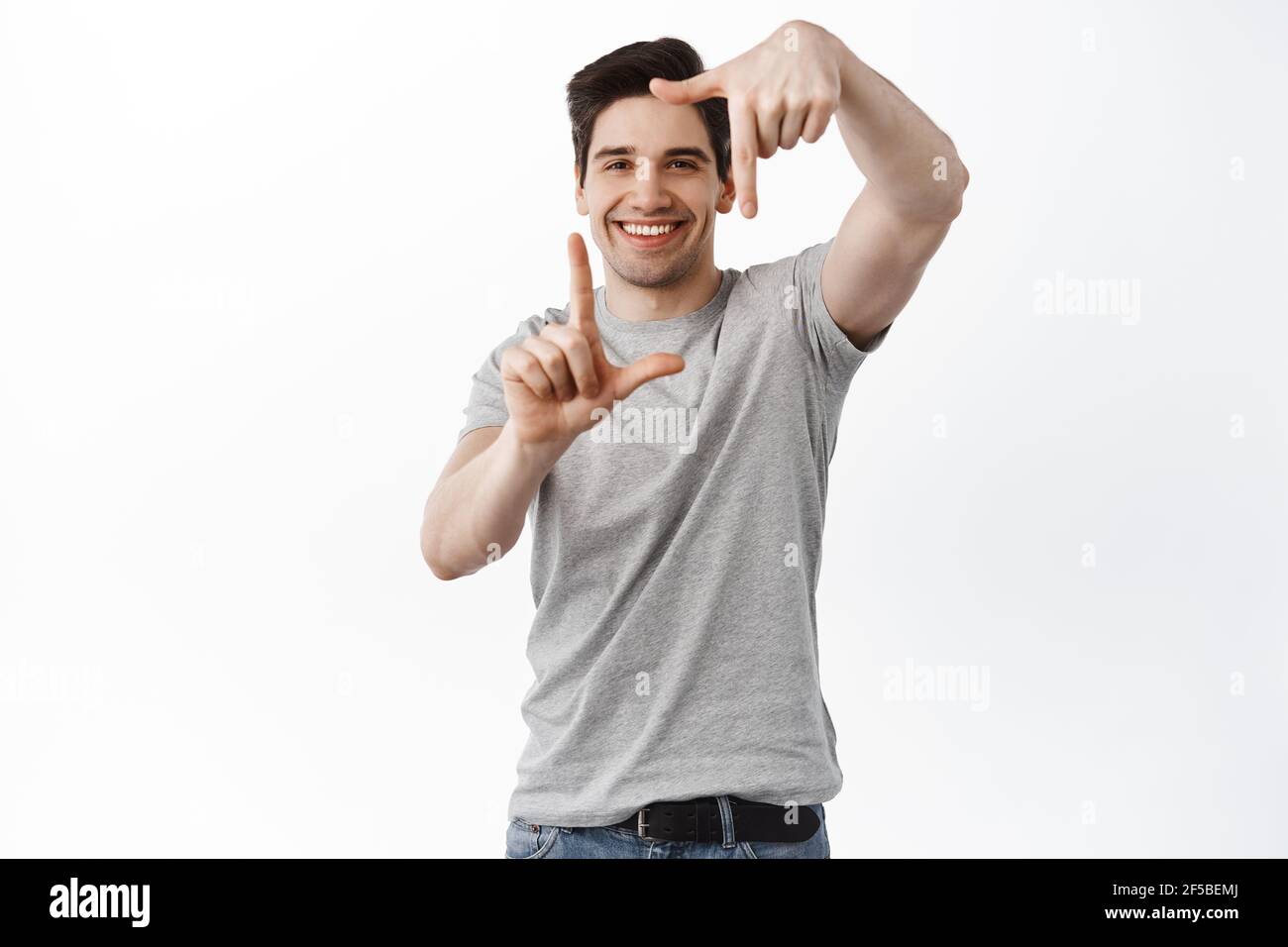 Handsome smiling man looking happy through hand frames camera gesture ...