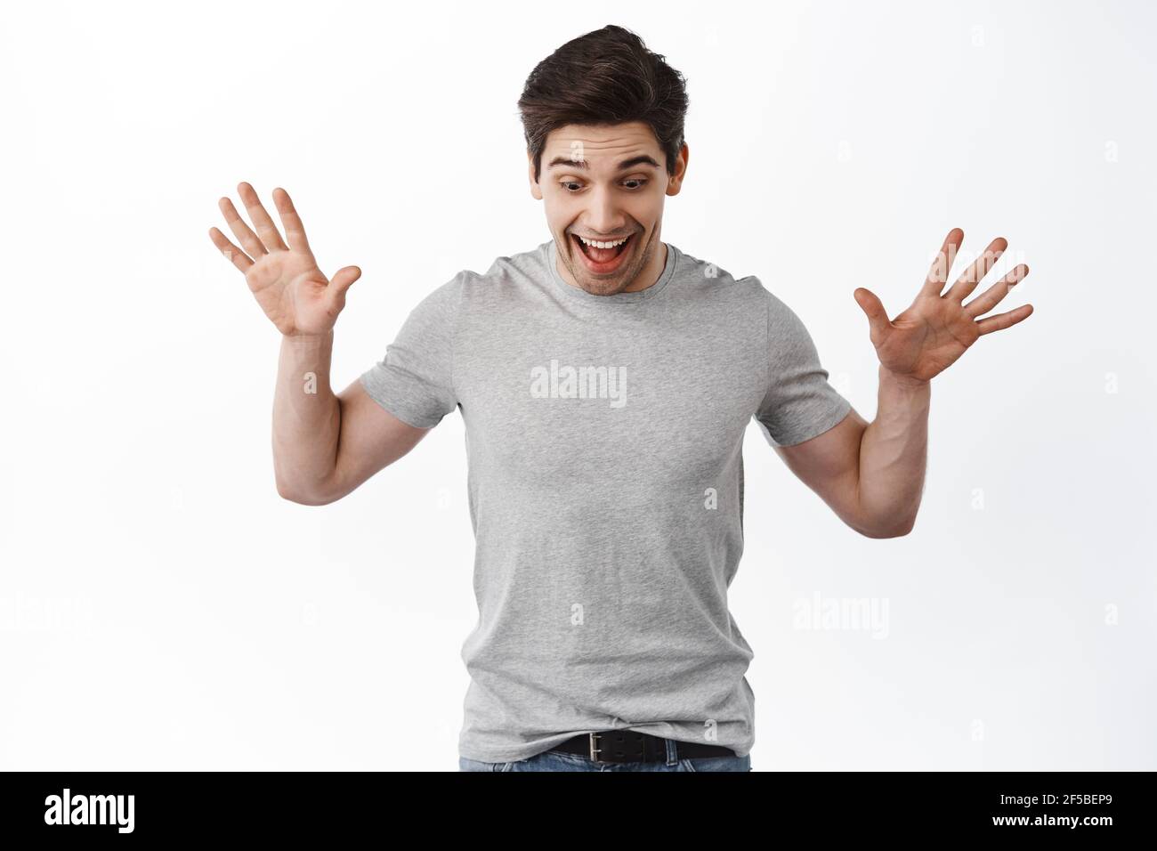 Portrait of excited man raise hands and look amazed down, found ...