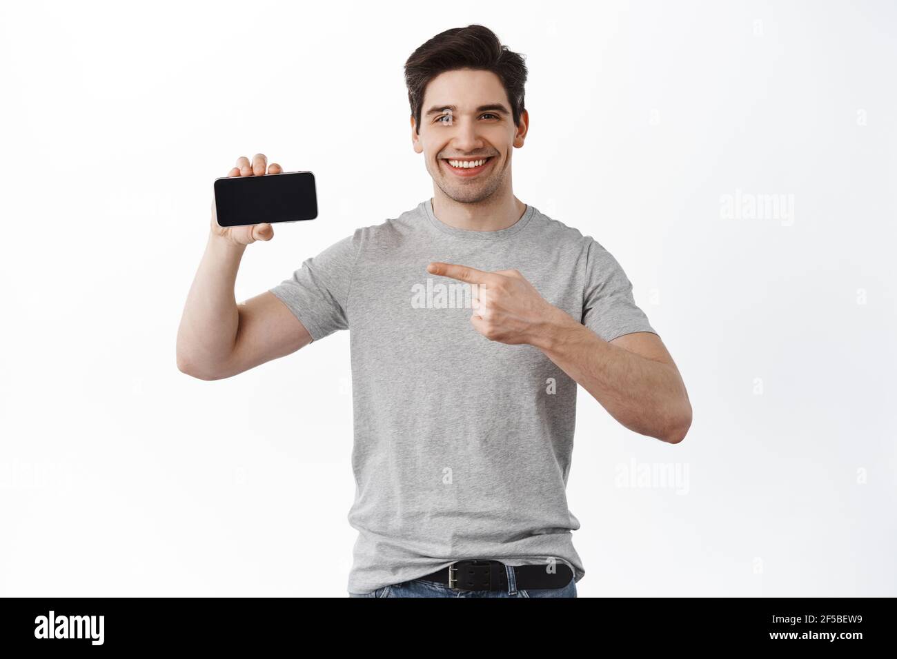 Smiling man pointing at smartphone screen, showing app or logo on ...