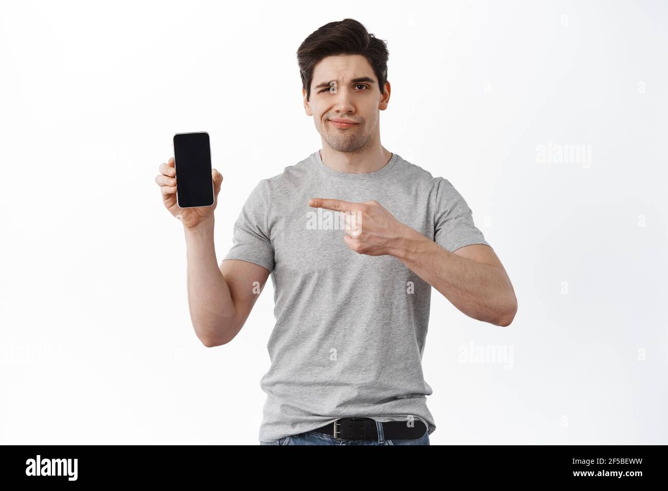 Disappointed guy complain on app, pointing at mobile phone screen ...