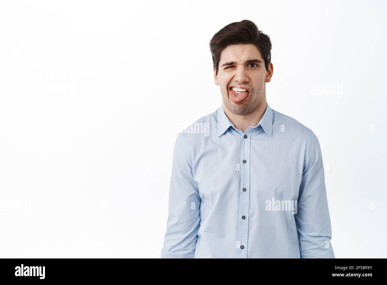 Confused and disgusted young man, office guy showing tongue and ...