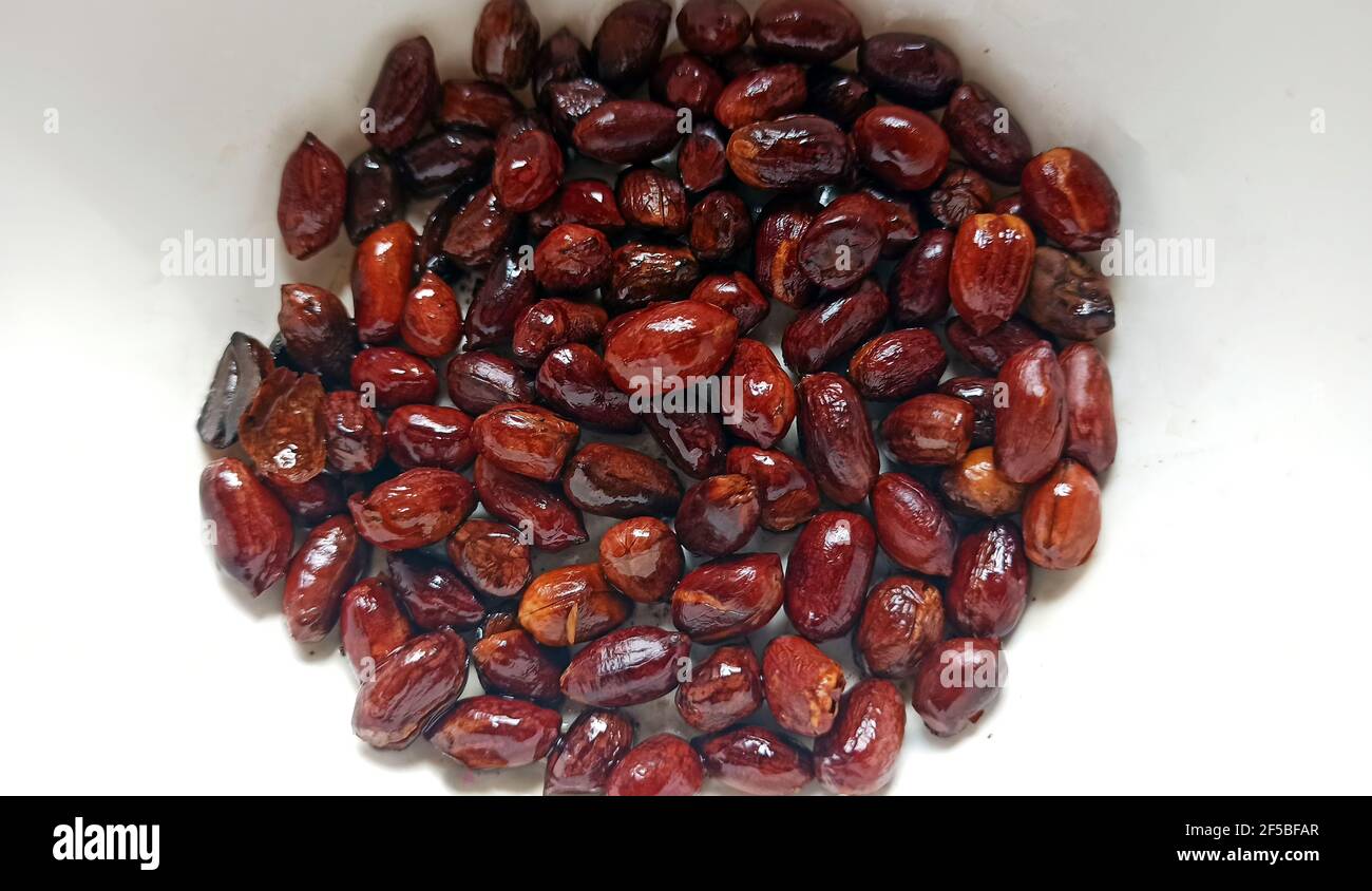 Close up image of fried peanuts inside a white bowl. shiny nuts against ...